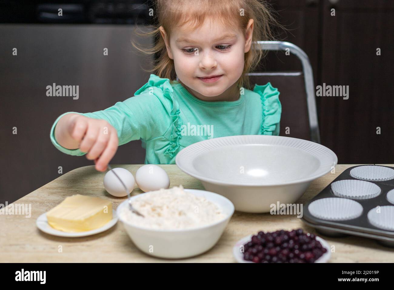 Little kid cooking food. Small child baking cupcakes at home sitting at ...