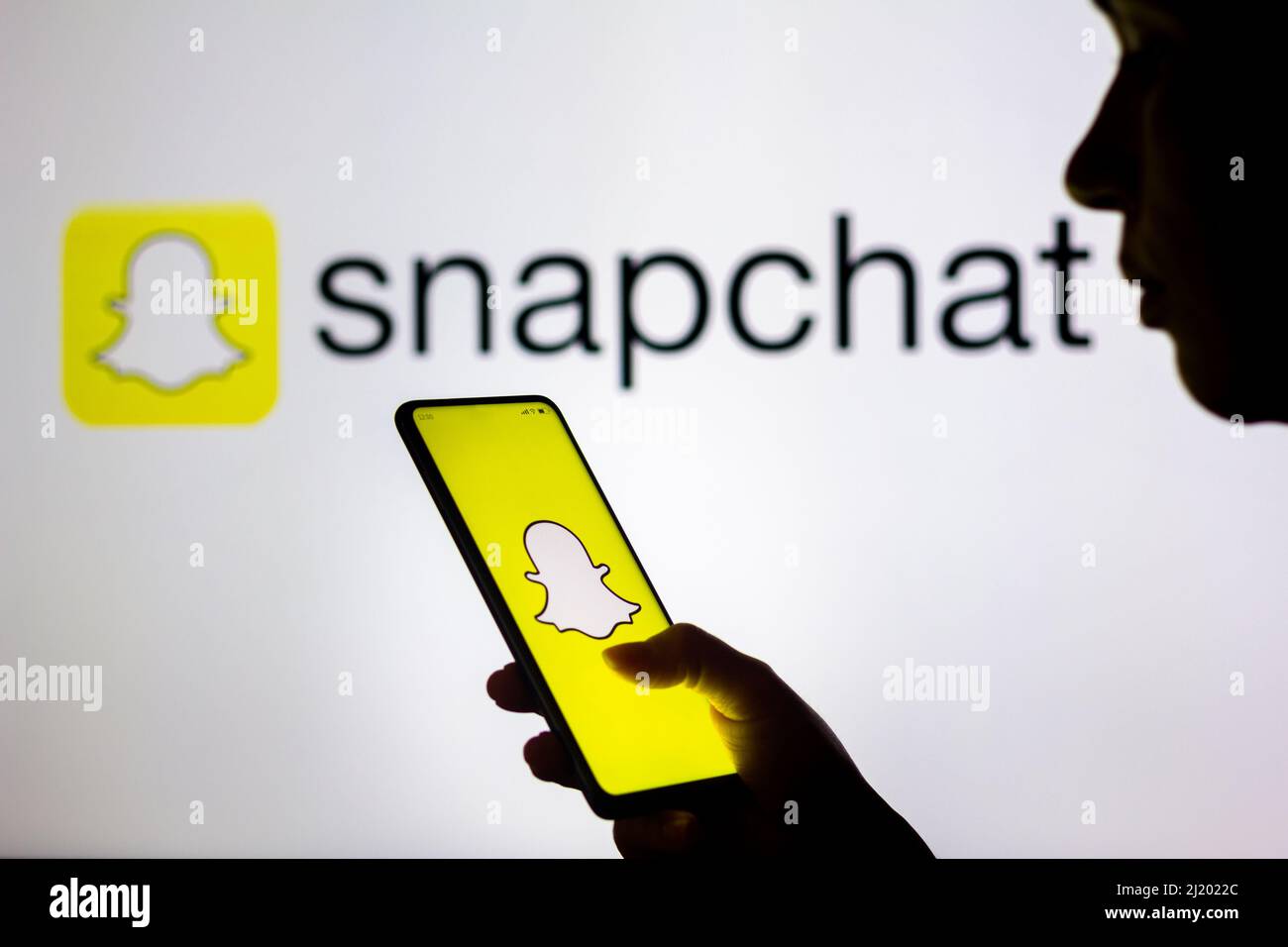 In this photo illustration, a woman's silhouette holds a smartphone ...