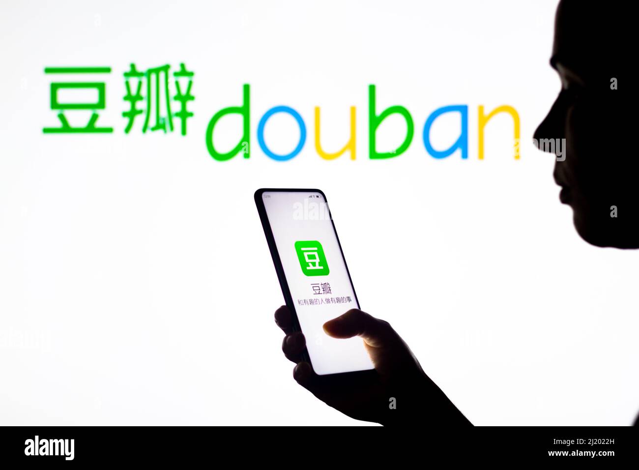 In this photo illustration, a woman's silhouette holds a smartphone with the Douban logo ...