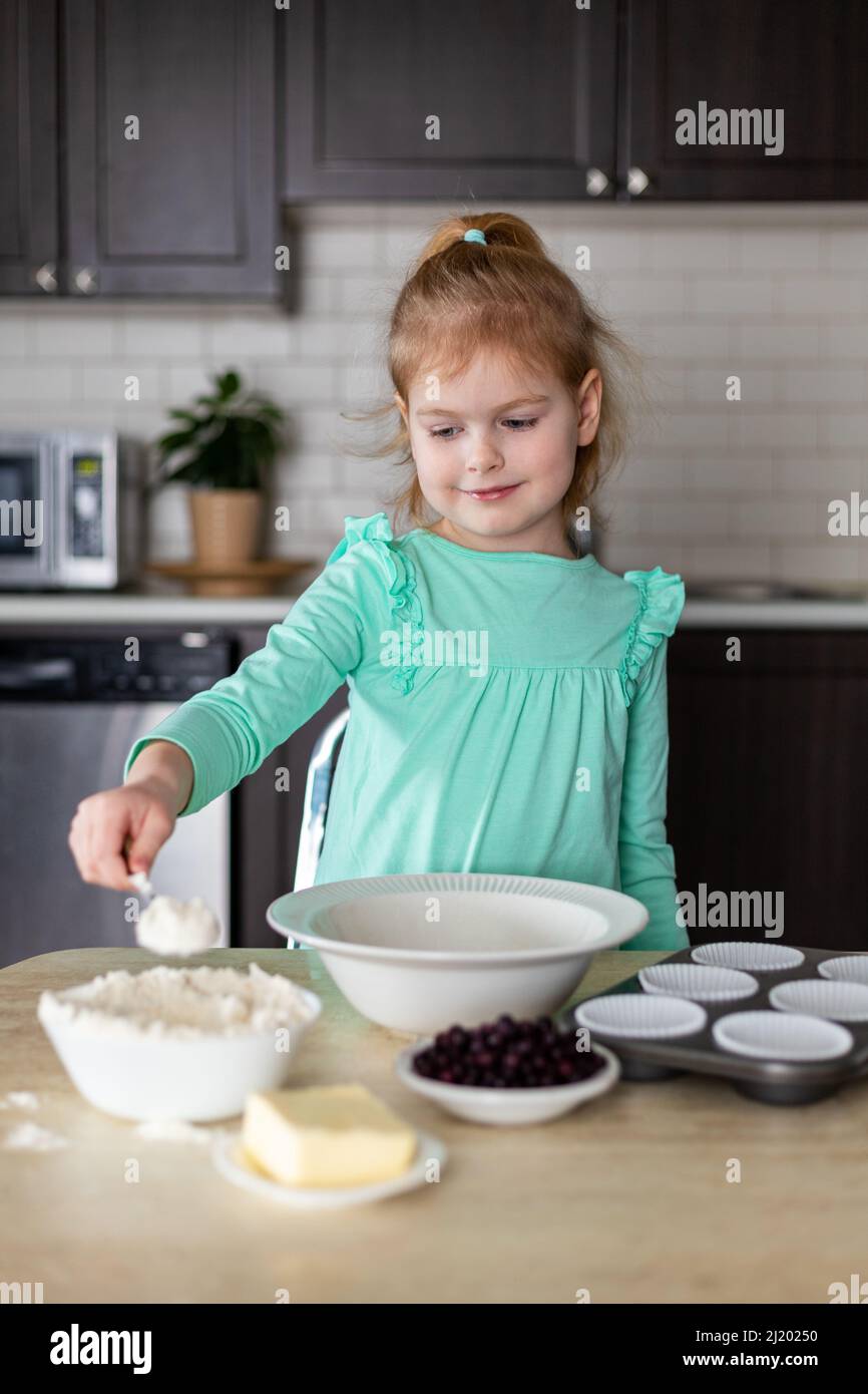 Little smiling girl mixing ingredients for baking homemade muffins ...