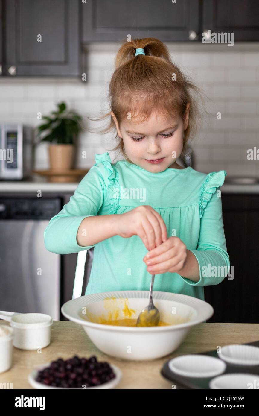 Little girl making dough for baking homemade muffins. Child cooking in ...