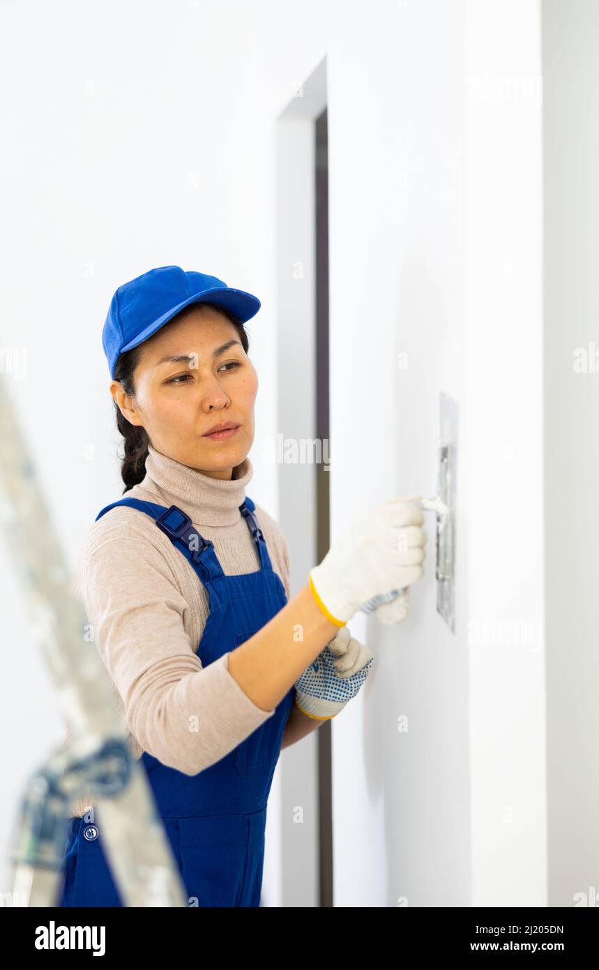 Woman builder using floated trowel to daub plaster to wall Stock Photo ...