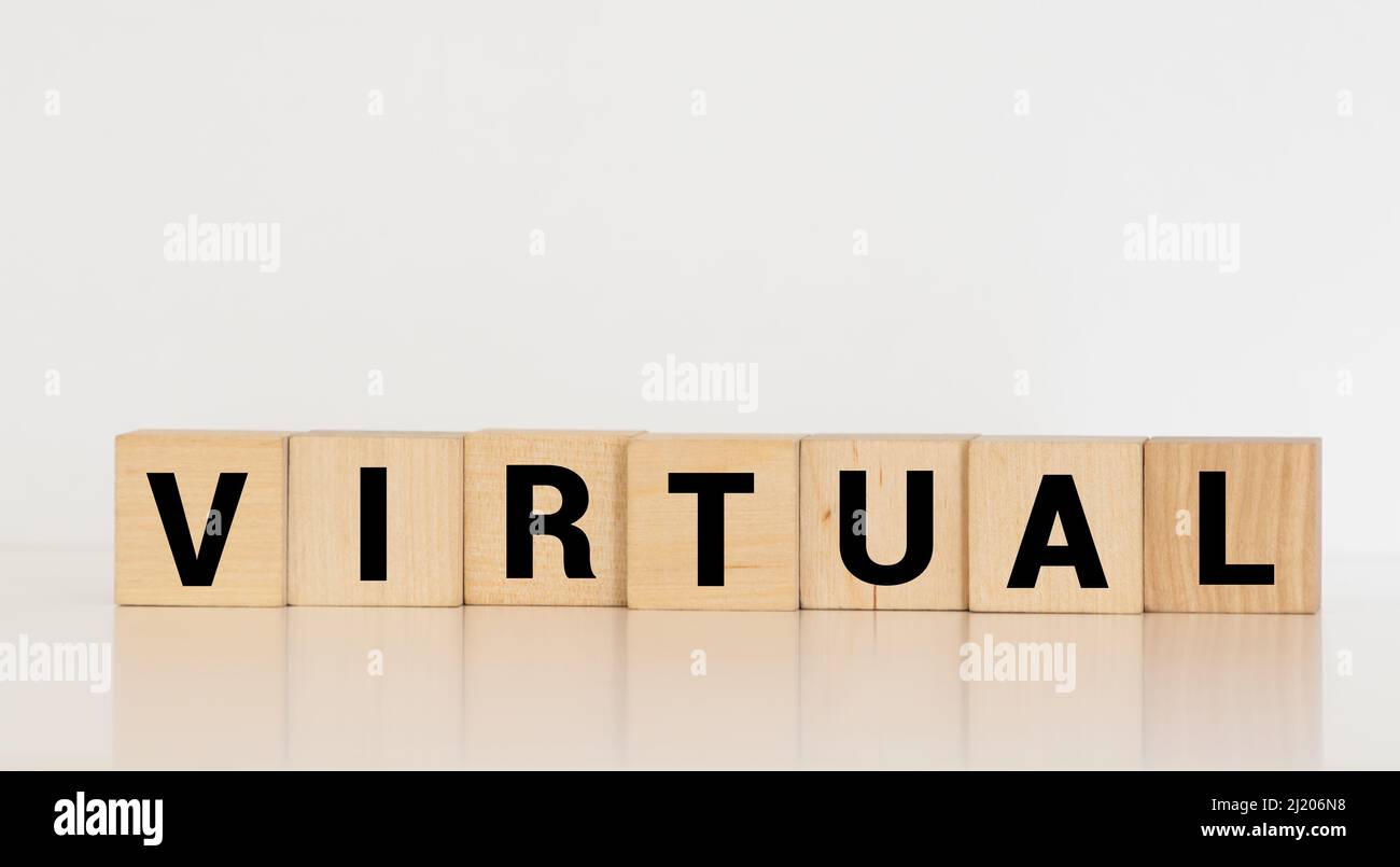 The word VIRTUAL is written on a wooden block on a computer keyboard ...