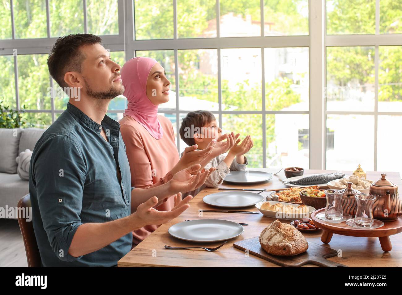 Muslim family praying together before breakfast. Celebration of Eid al ...