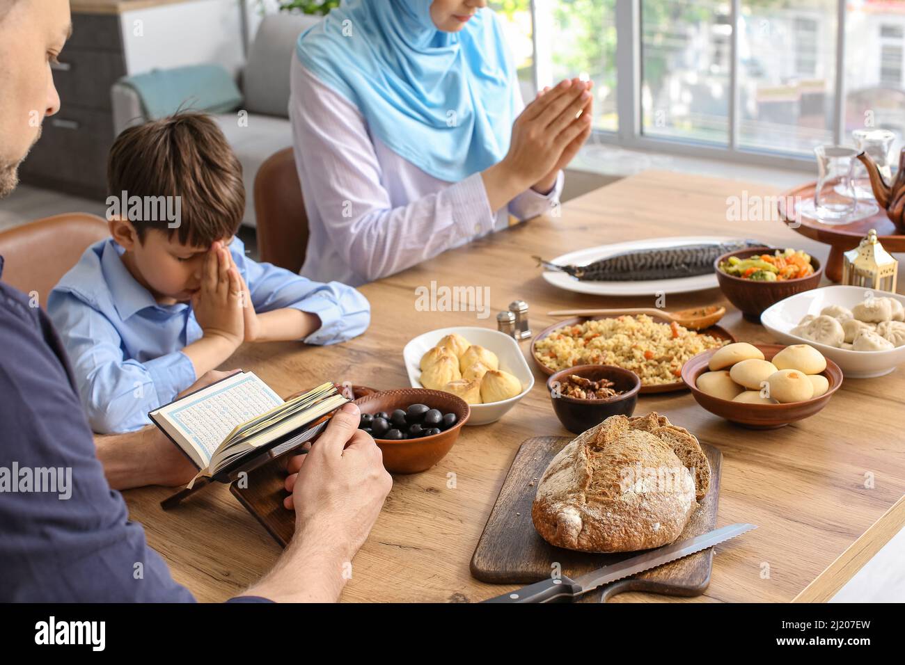 Muslim family praying together before breakfast. Celebration of Eid al ...
