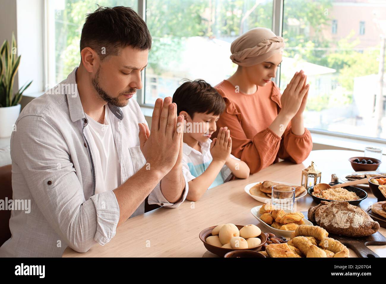 Muslim family praying together before breakfast. Celebration of Eid al ...