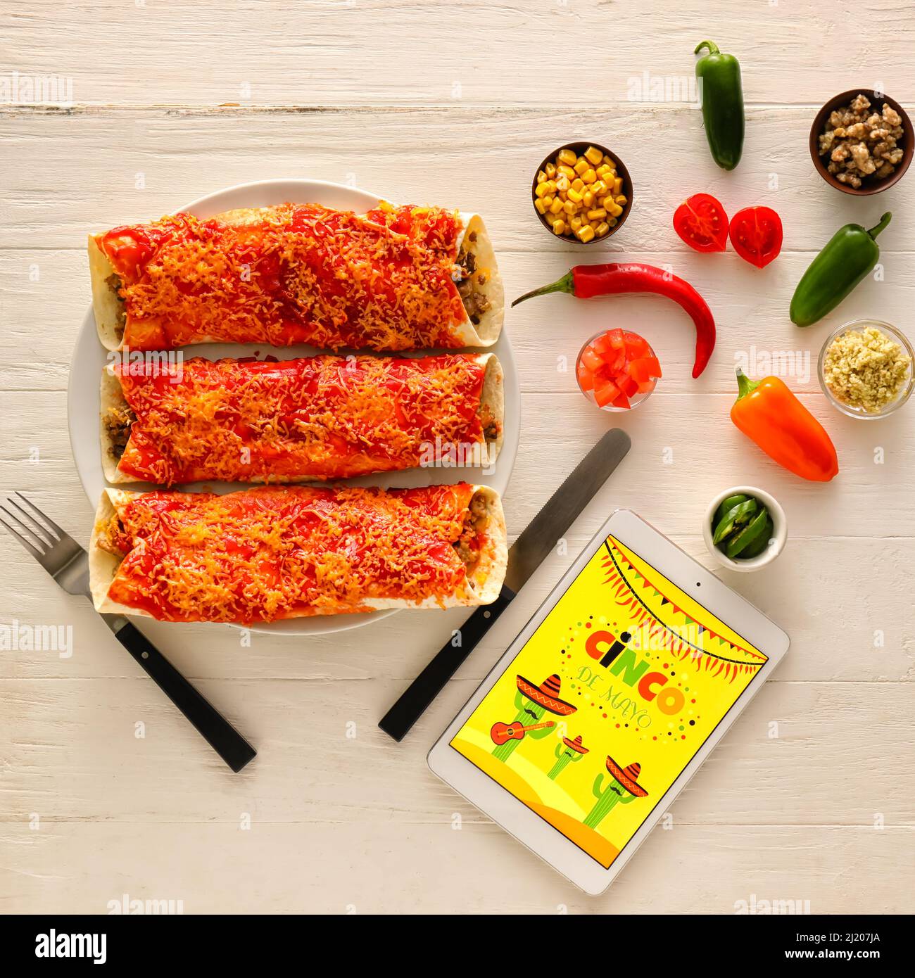 Traditional Mexican enchilada and tablet computer on white wooden ...