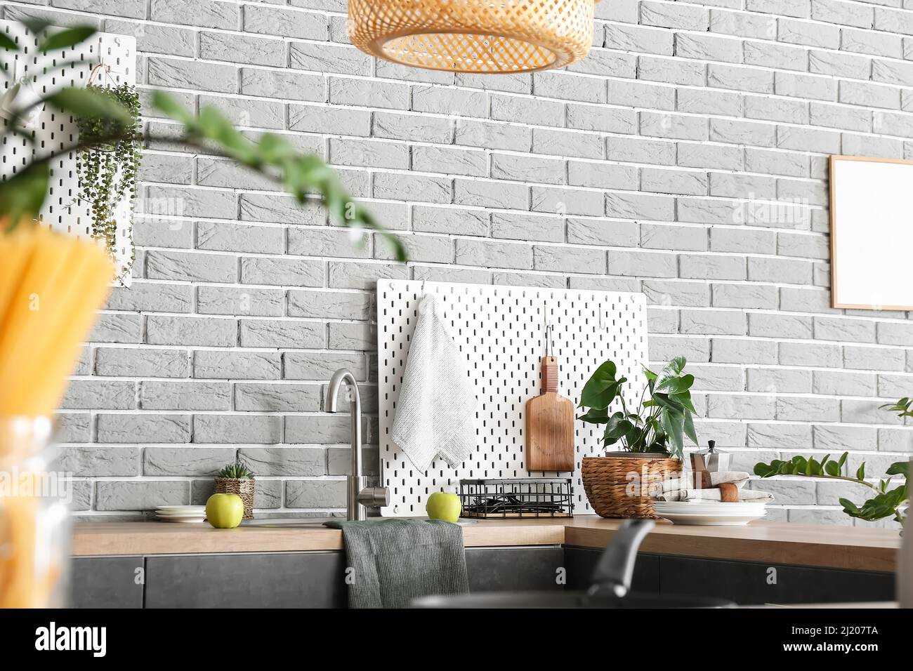 Stylish counter and pegboard on grey brick wall in modern kitchen Stock ...
