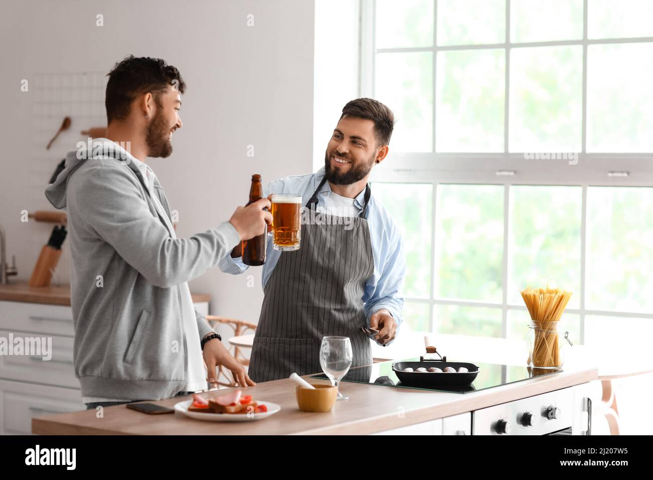 Young brothers drinking beer in kitchen Stock Photo - Alamy