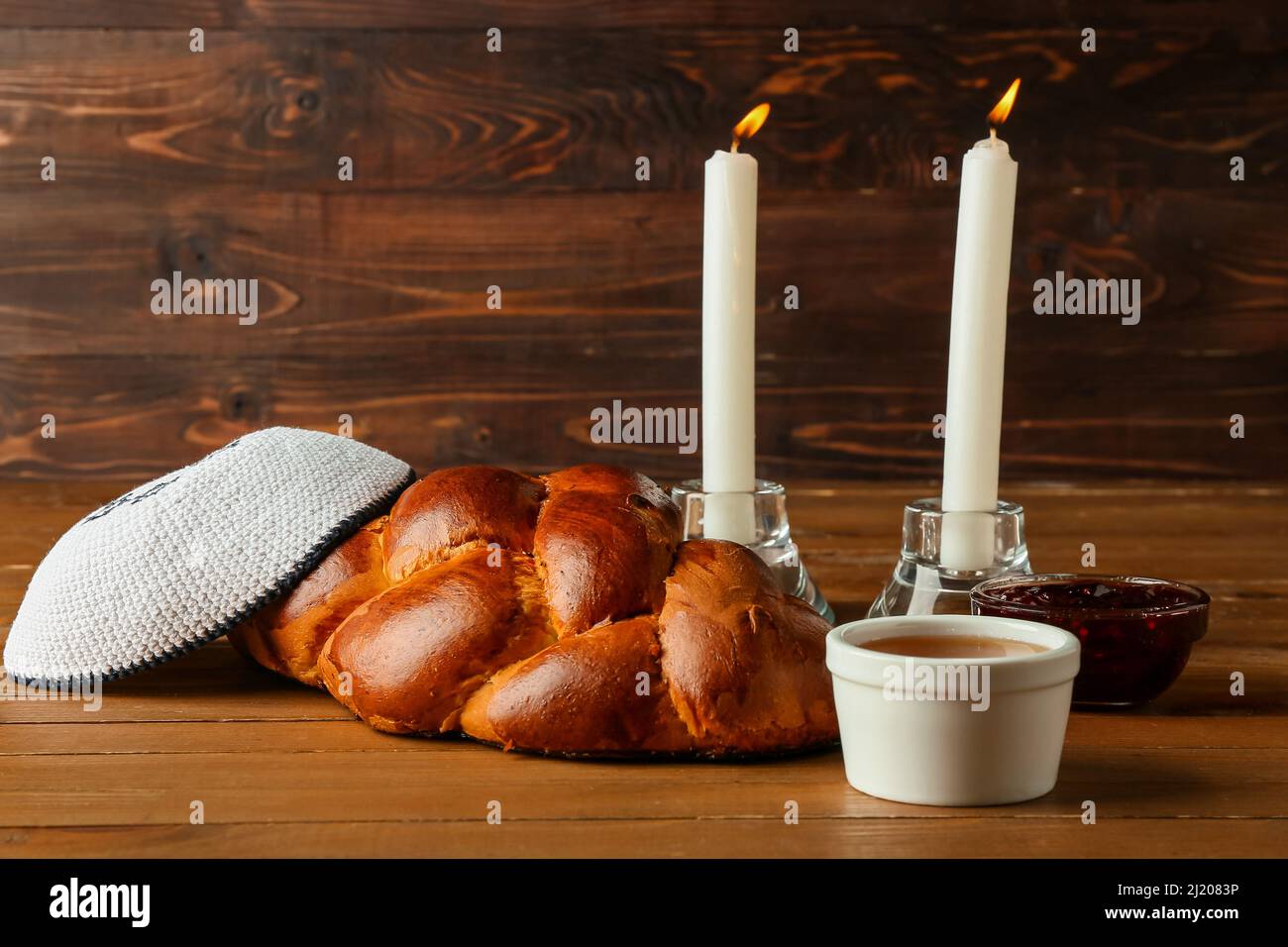 Traditional challah bread with glowing candles and Jewish cap on wooden ...