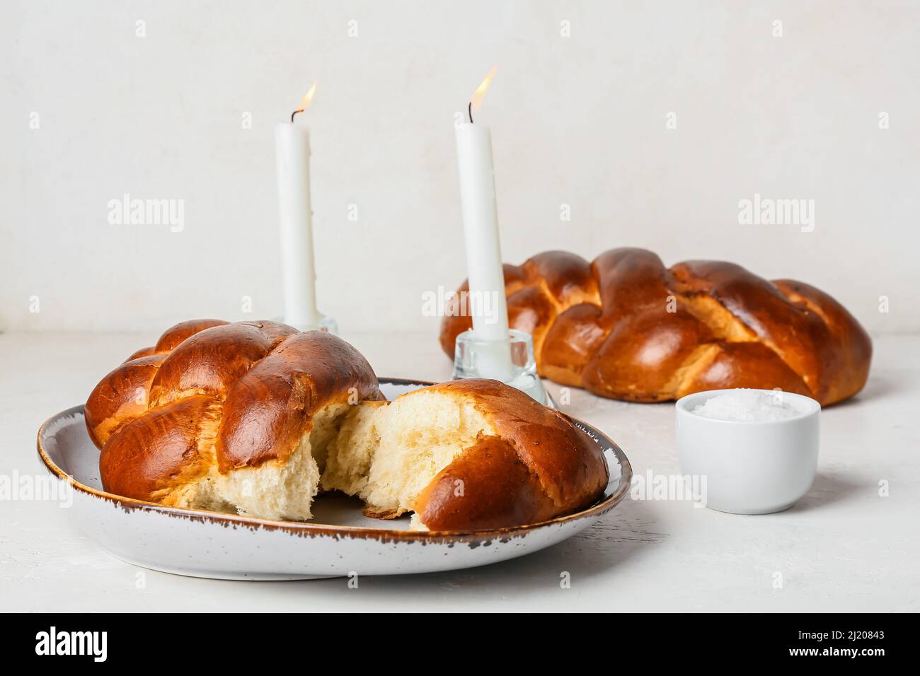 Traditional challah bread with glowing candles on white background ...