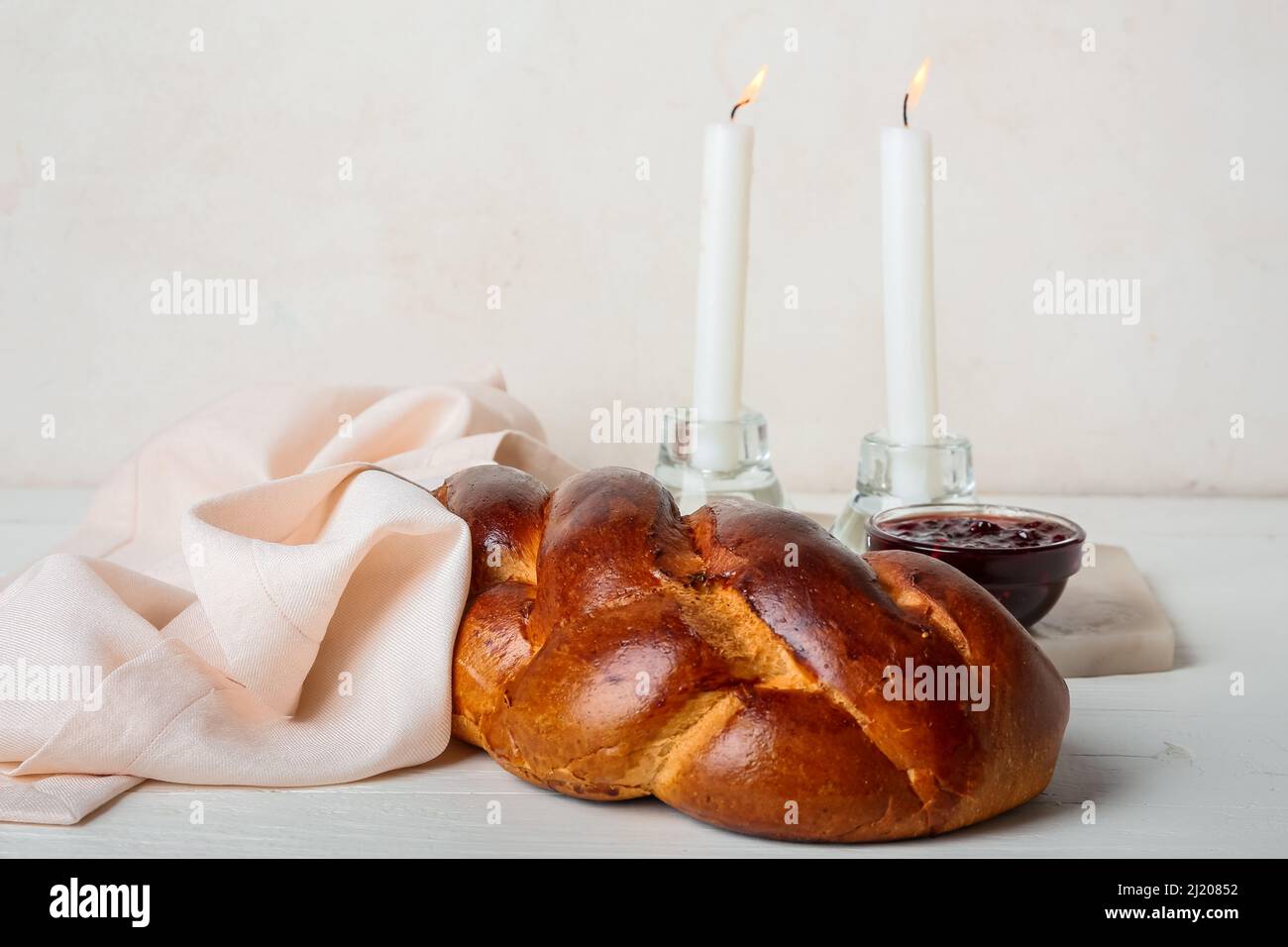 Traditional challah bread with glowing candles on white background ...
