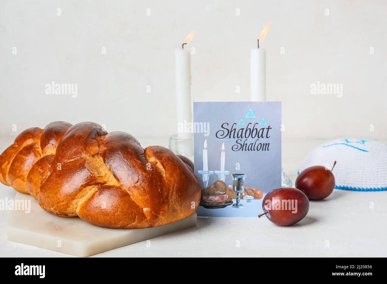 Traditional challah bread with greeting card and candles on white ...