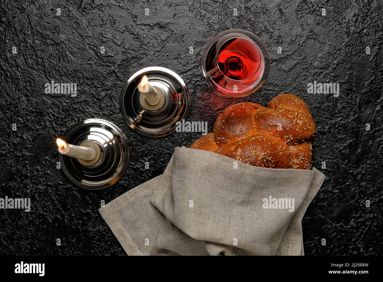 Traditional challah bread with glass of wine and candles on dark ...