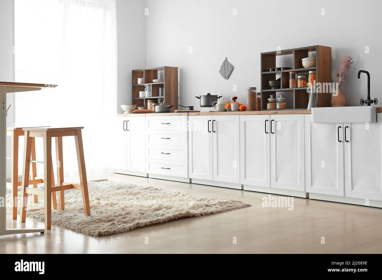 Interior of modern kitchen with white counters, shelving units and ...