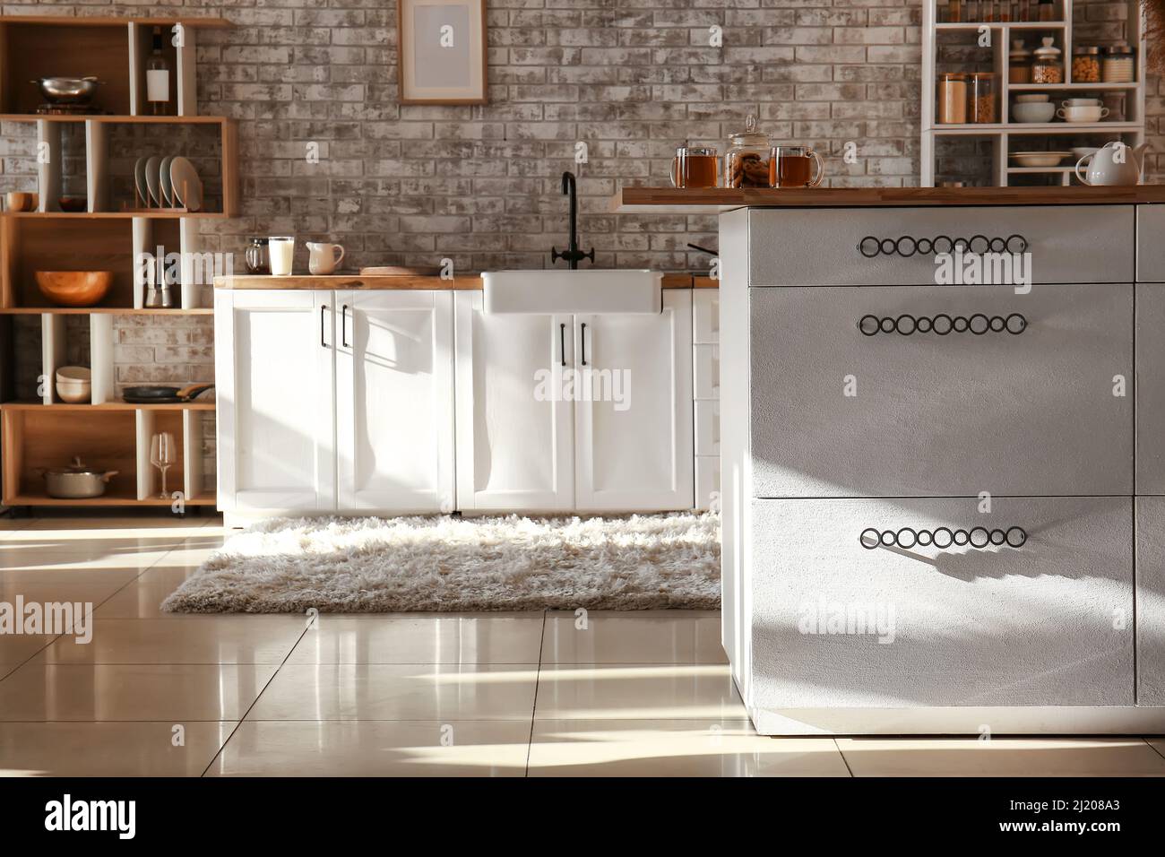 Interior of modern kitchen with white counters, shelving units and ...