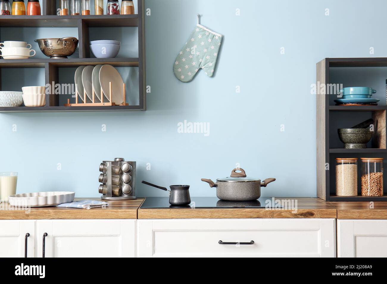 Stove with cooking pot and cezve near blue wall in kitchen Stock Photo ...