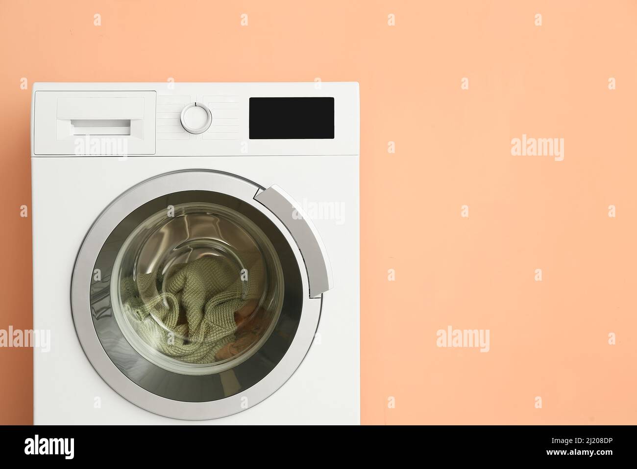 Modern washing machine with laundry near wall Stock Photo - Alamy