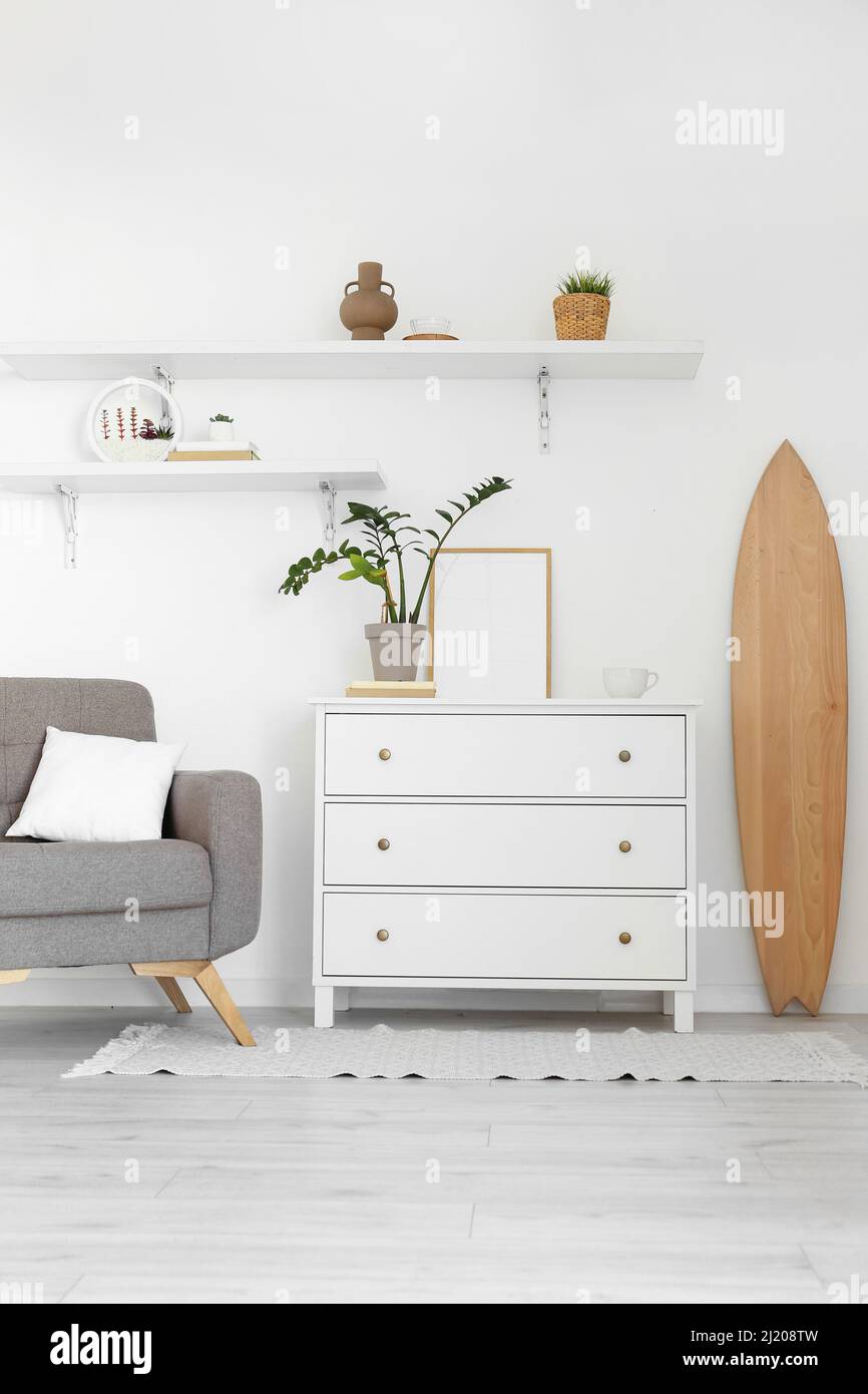 Interior of light living room with wooden surfboard, commode and ...