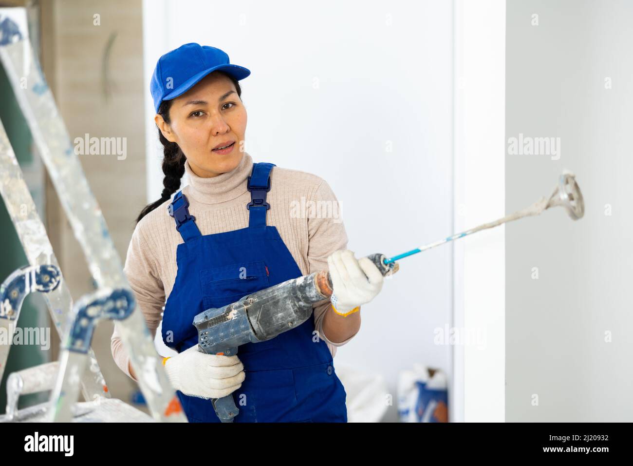 Portrait of female builder with paint mixing machine Stock Photo - Alamy