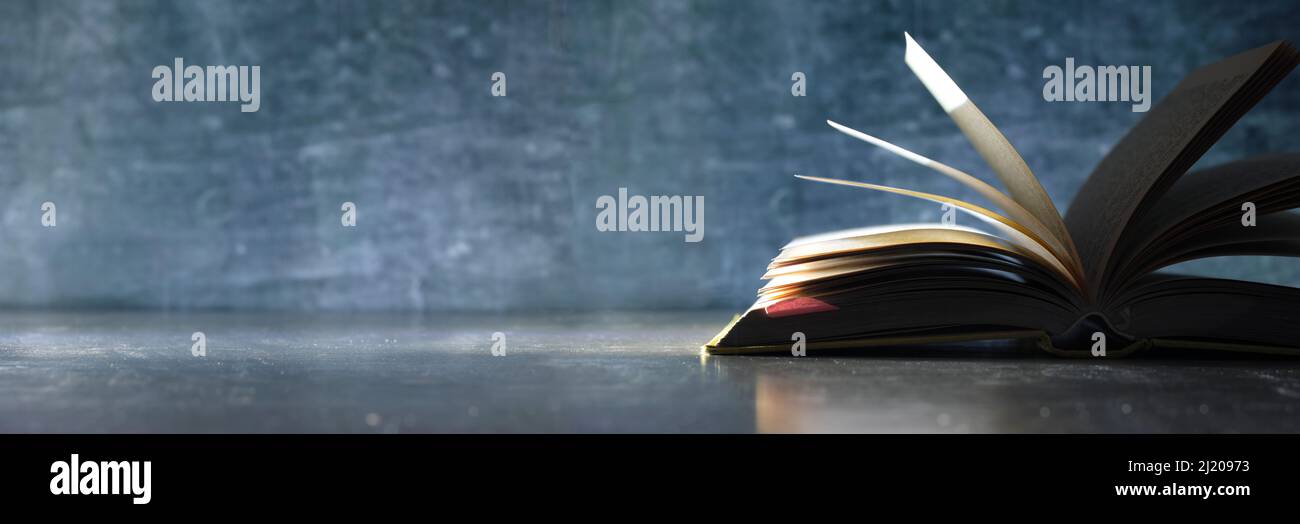 Open book, hardback book on wooden table on dark background. Home ...