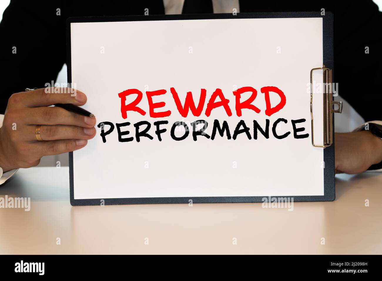 Business concept. Notebook with text REWARD PERFORMANCE sheet of white ...