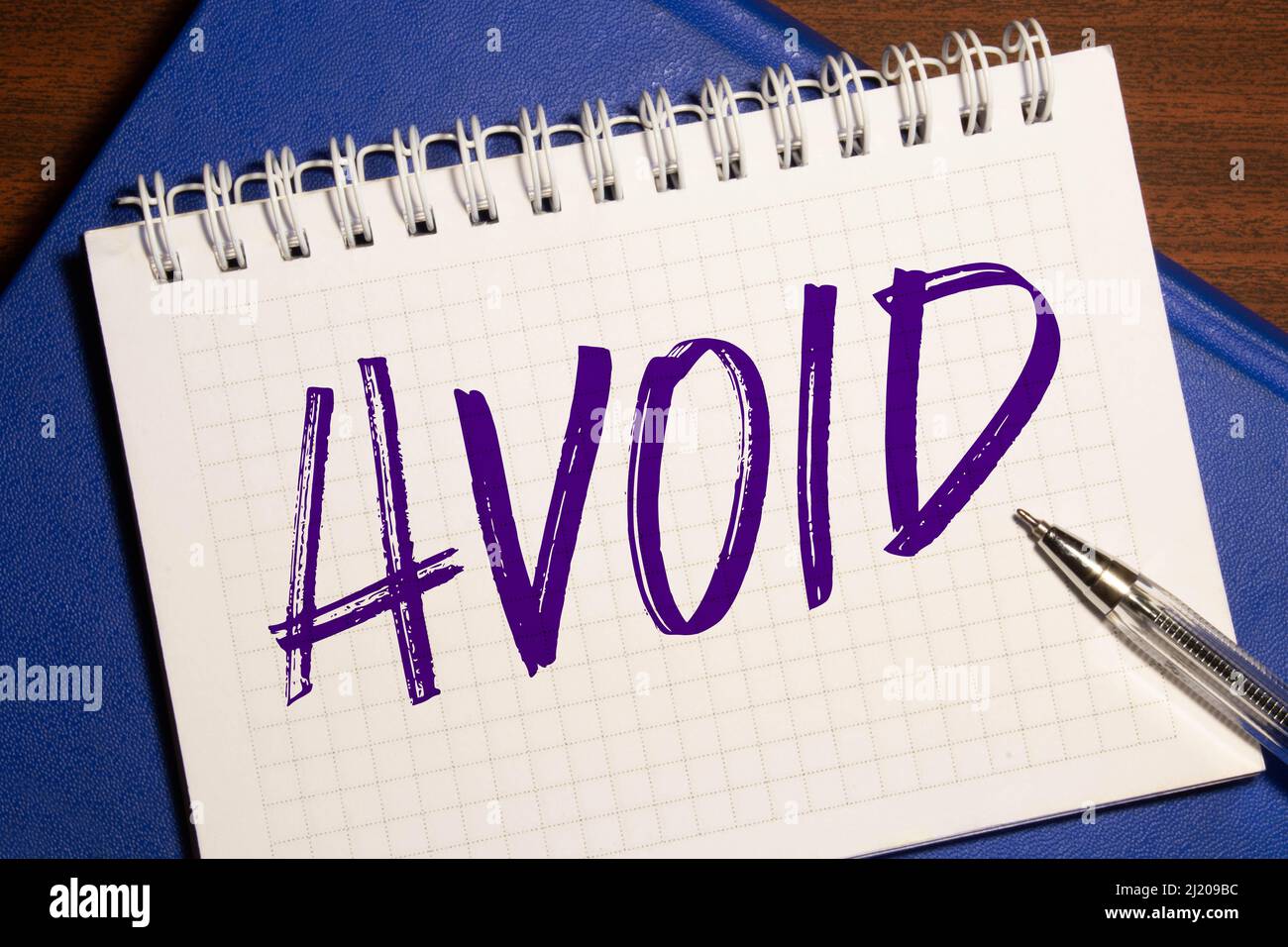 the word AVOID written in notepad, concept Stock Photo - Alamy