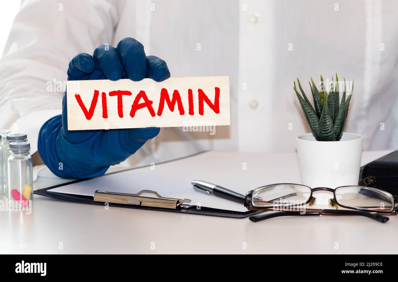 Vitamin written on a card in doctors hands Stock Photo - Alamy