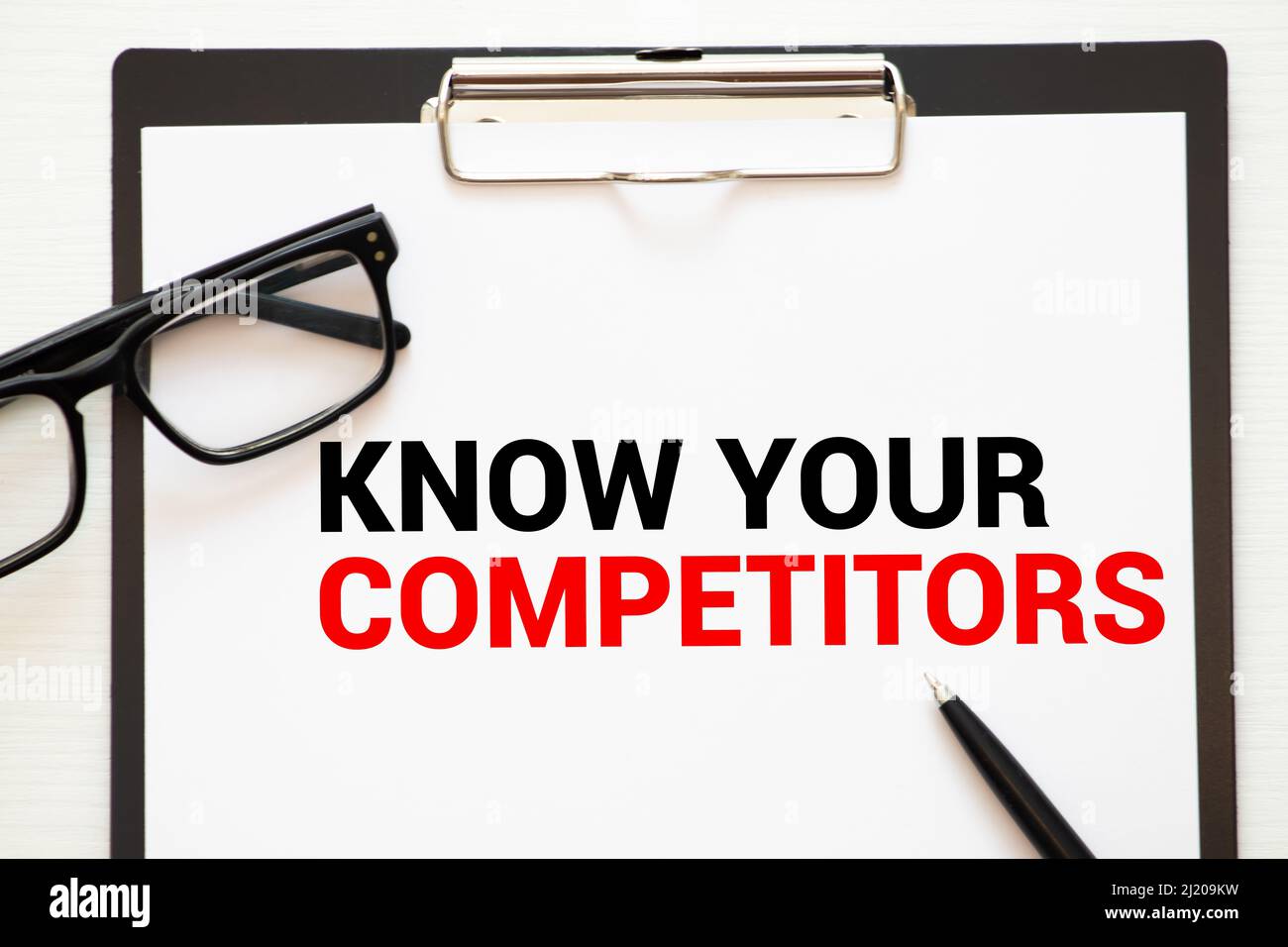 Businessman holding a card with text KNOW YOUR COMPETITORS. Keyboard ...