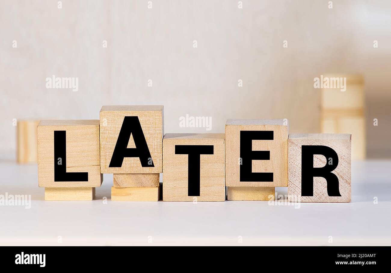 Wooden figures as business team in circle around word LATER, isolated ...