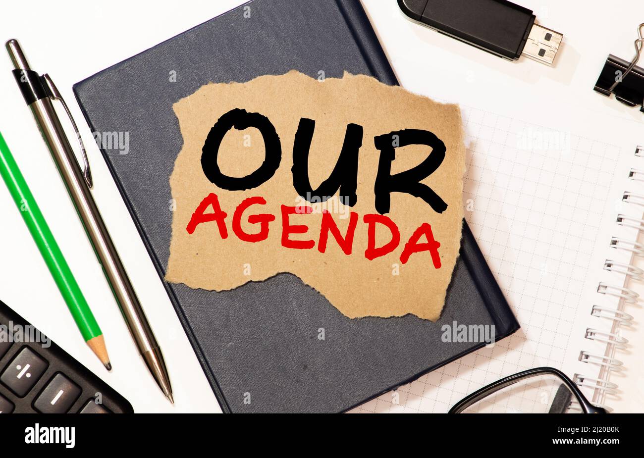 Sticky note writing Our Agenda on Office table with keyboard, dice, pen ...