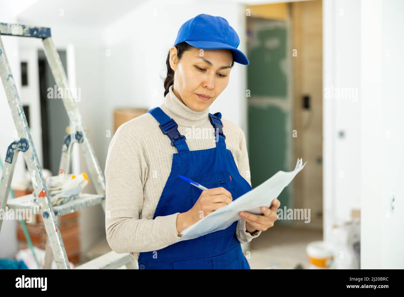 Female engineer writing in check list during repair works Stock Photo ...