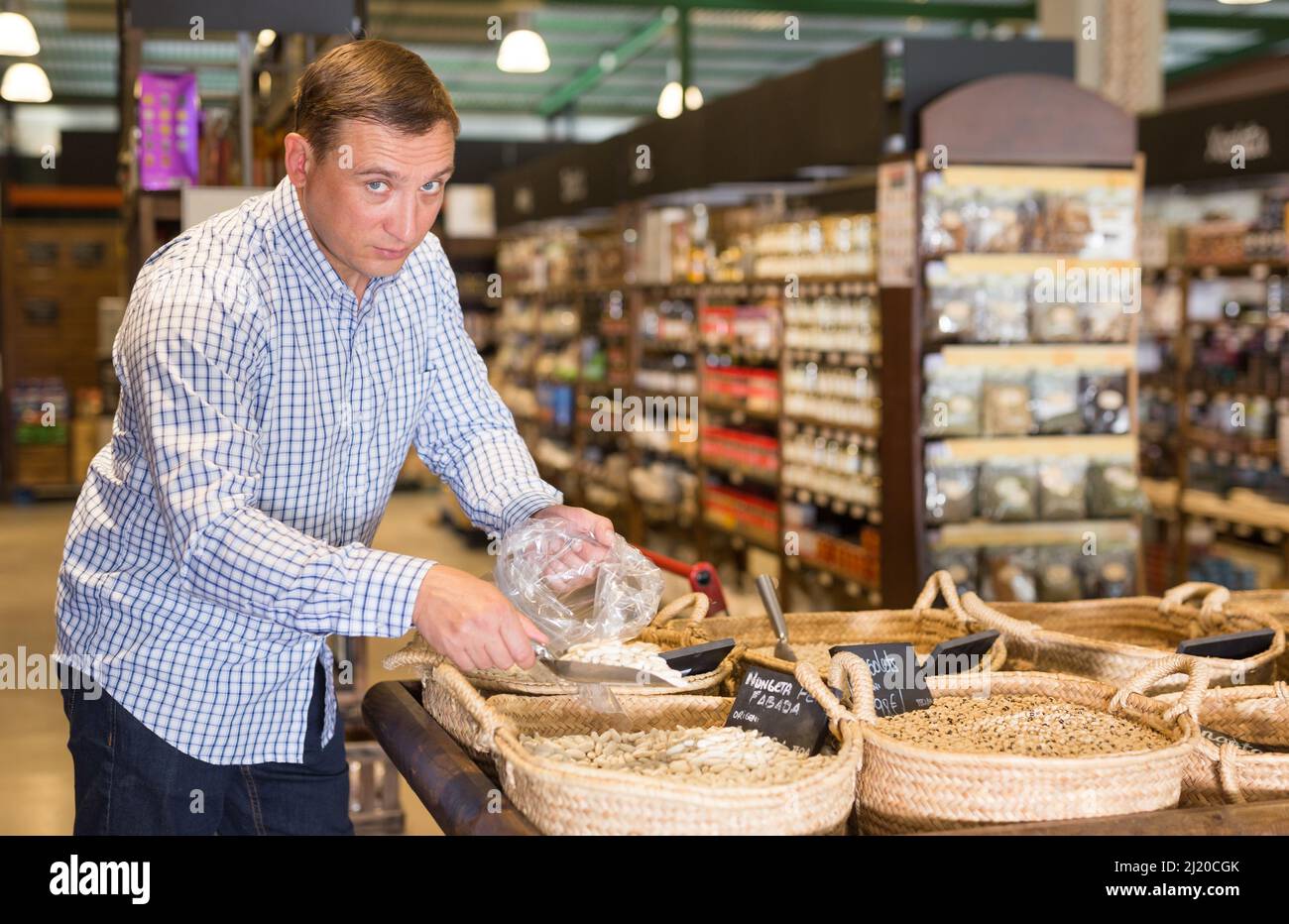 Male customer choosing nuts in average food shop Stock Photo - Alamy