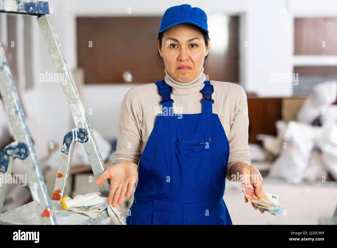 Frustrated woman builder is unhappy with earned money Stock Photo - Alamy