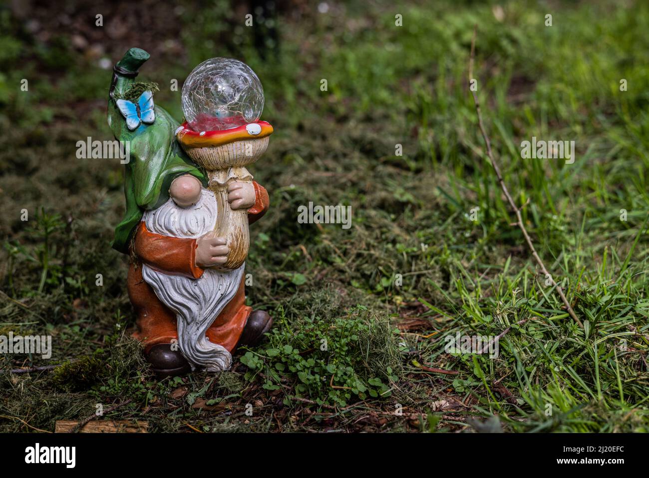Little man with beard holding up mushroom rod that is solar light in ...