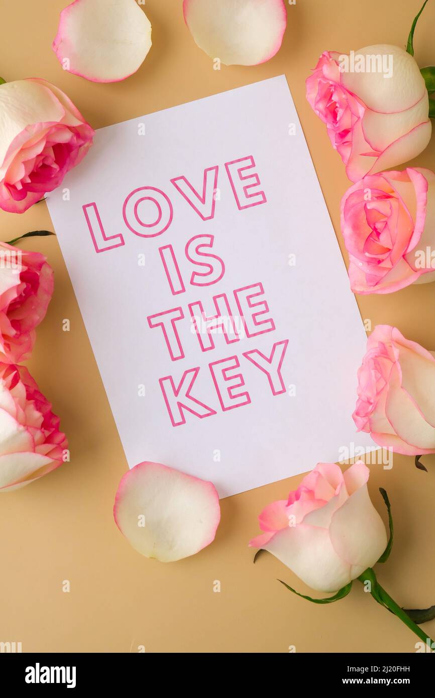 LOVE IS THE KEY text on greeting card paper note. Delicate pink roses ...