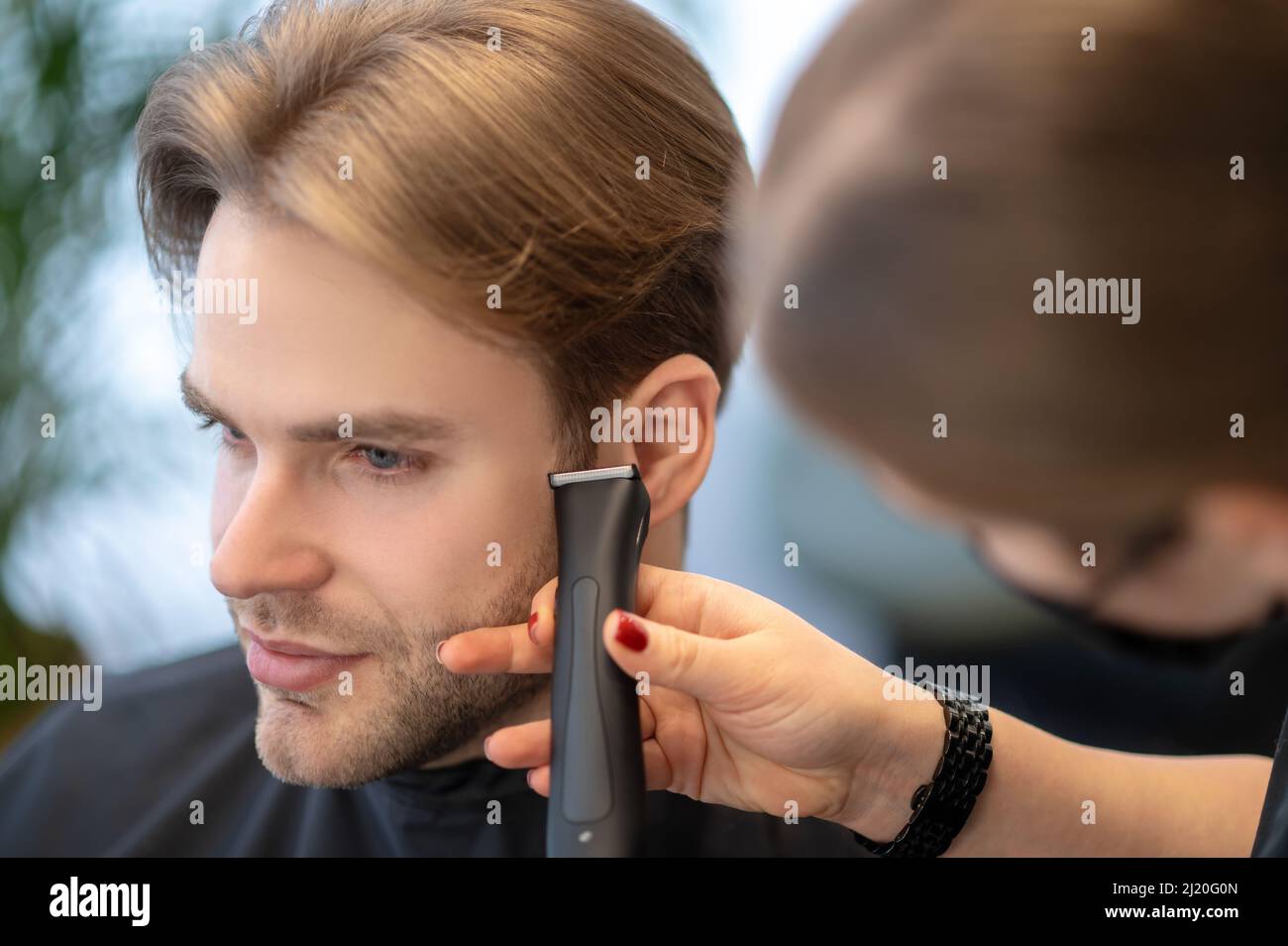 Fair-haired man having hairstyling procedures at the beauty salon Stock ...