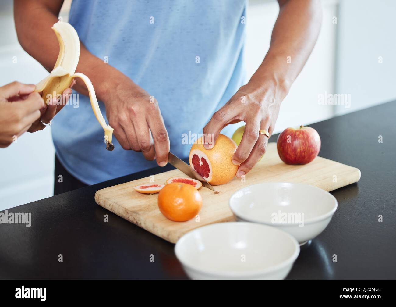 Summer is the best time for fruit. Shot of a couple peeling and cutting ...