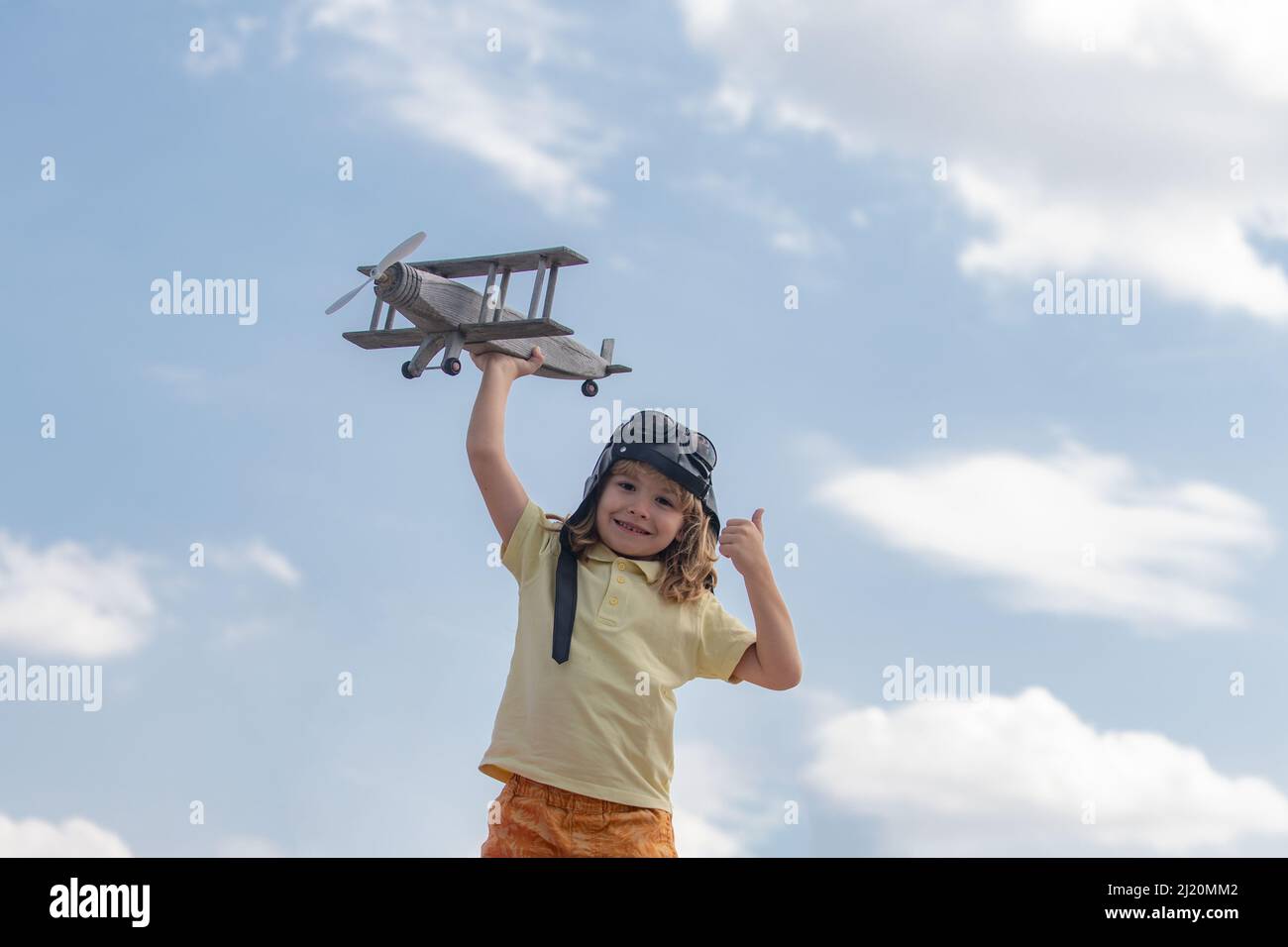 Child boy with pilot goggles and helmet playing with wooden toy ...