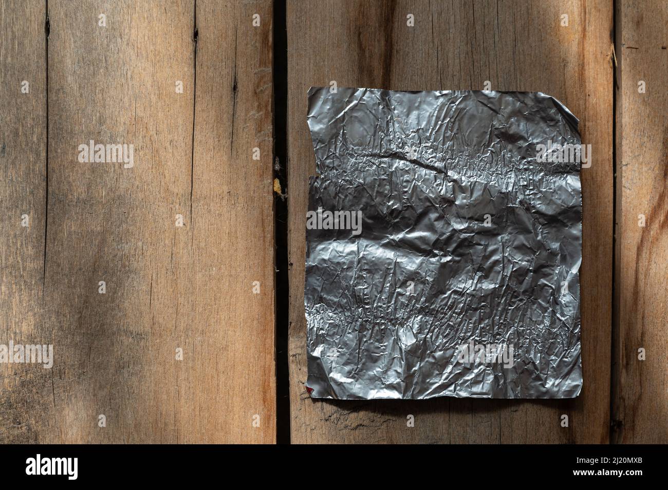 Rectangular aluminum candy wrapper against a wooden background. Rough ...