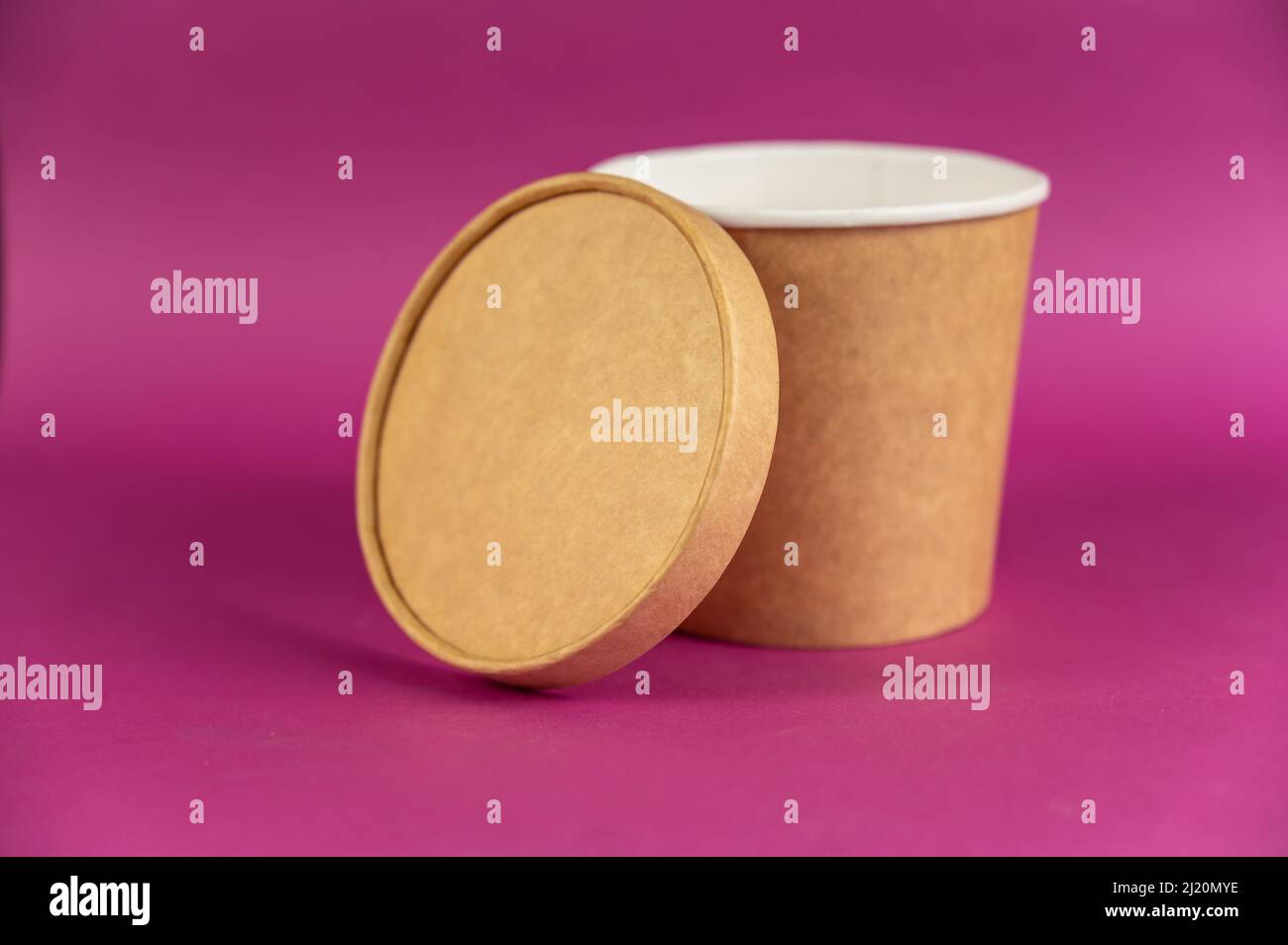 Empty cylindrical paper container with lid opposite-colored background ...