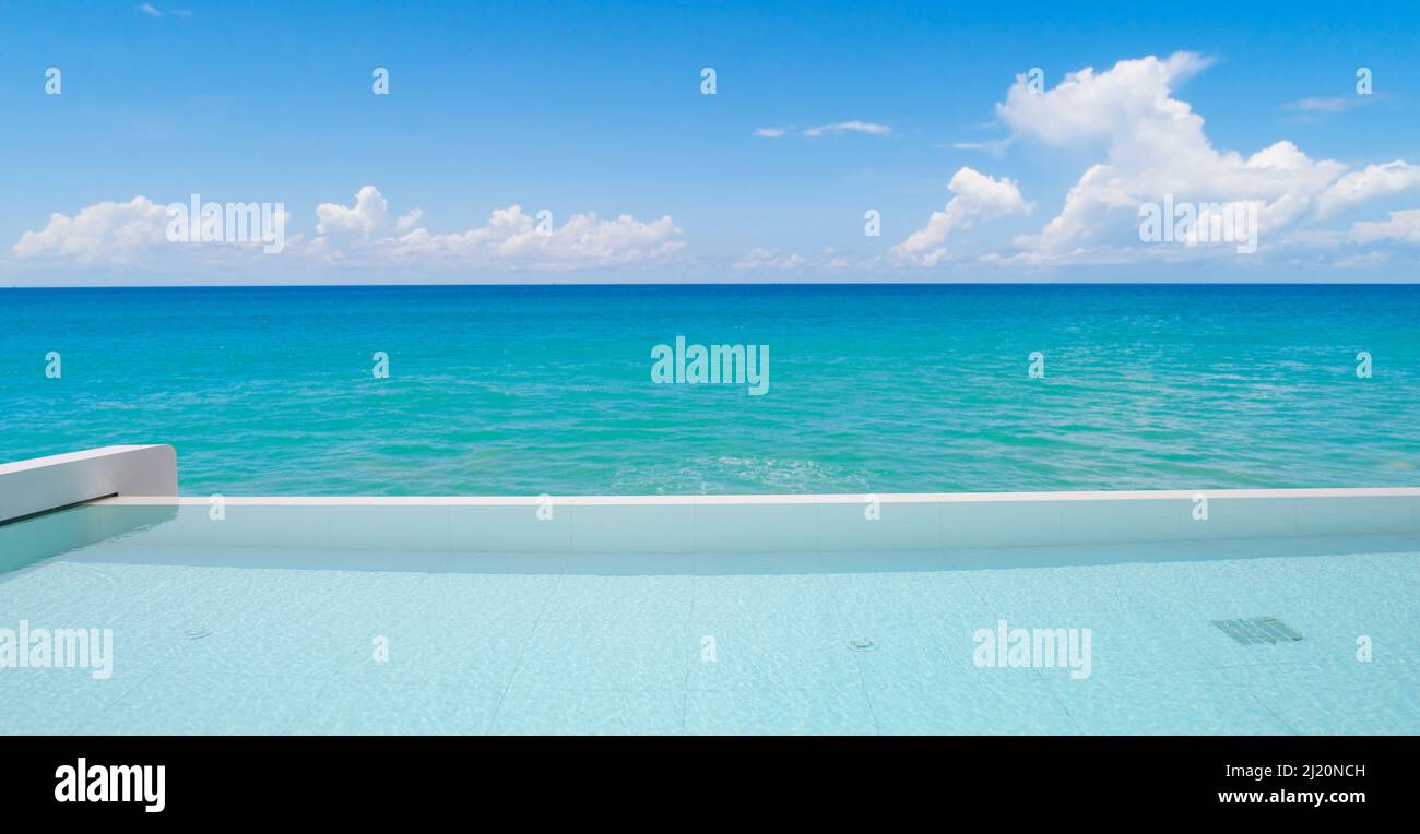 Swimming pool overlooking view tropical sea and clear blue sky ...
