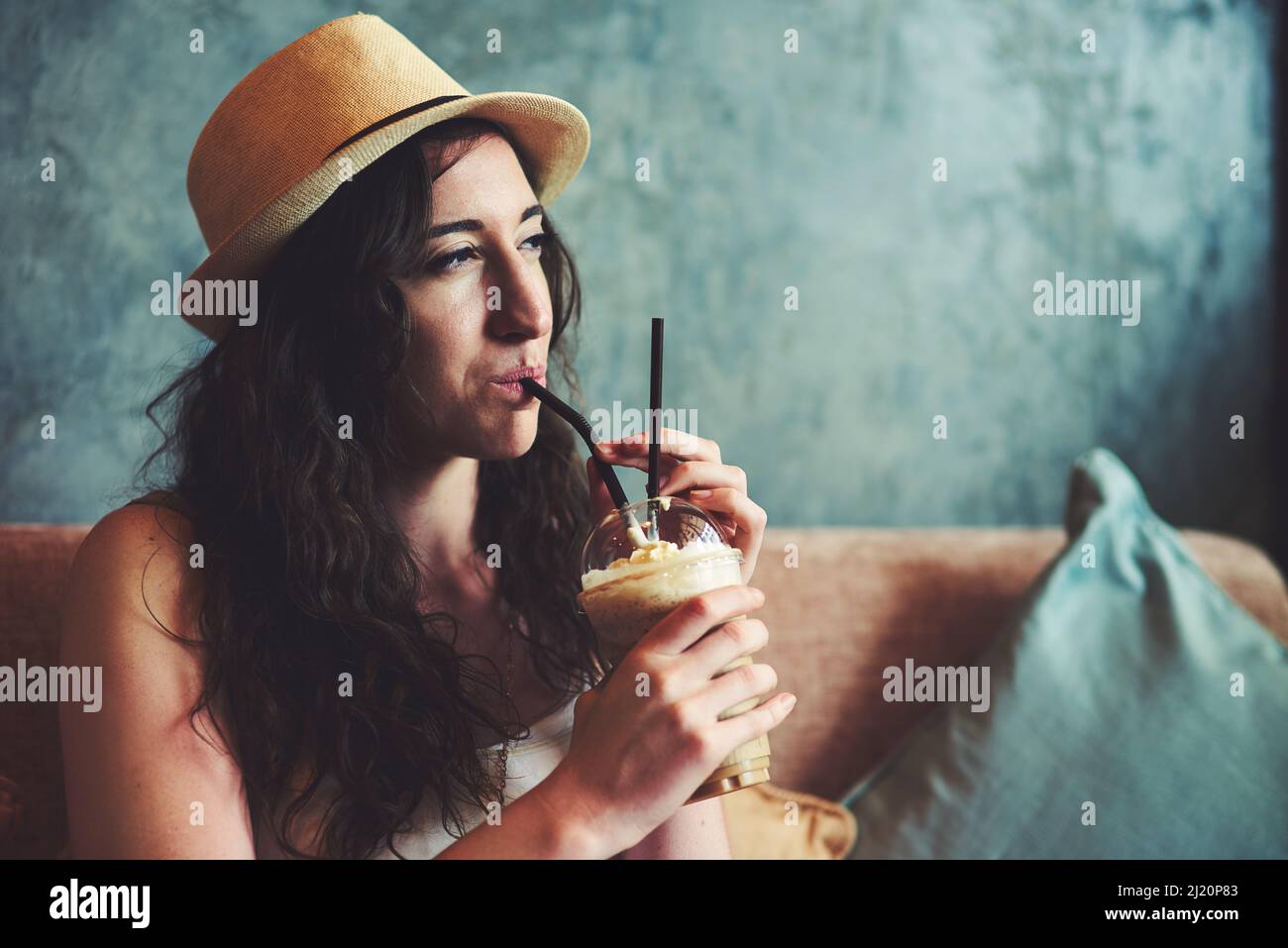 Sipping on something sweet. Shot of a young woman enjoying a chilled ...