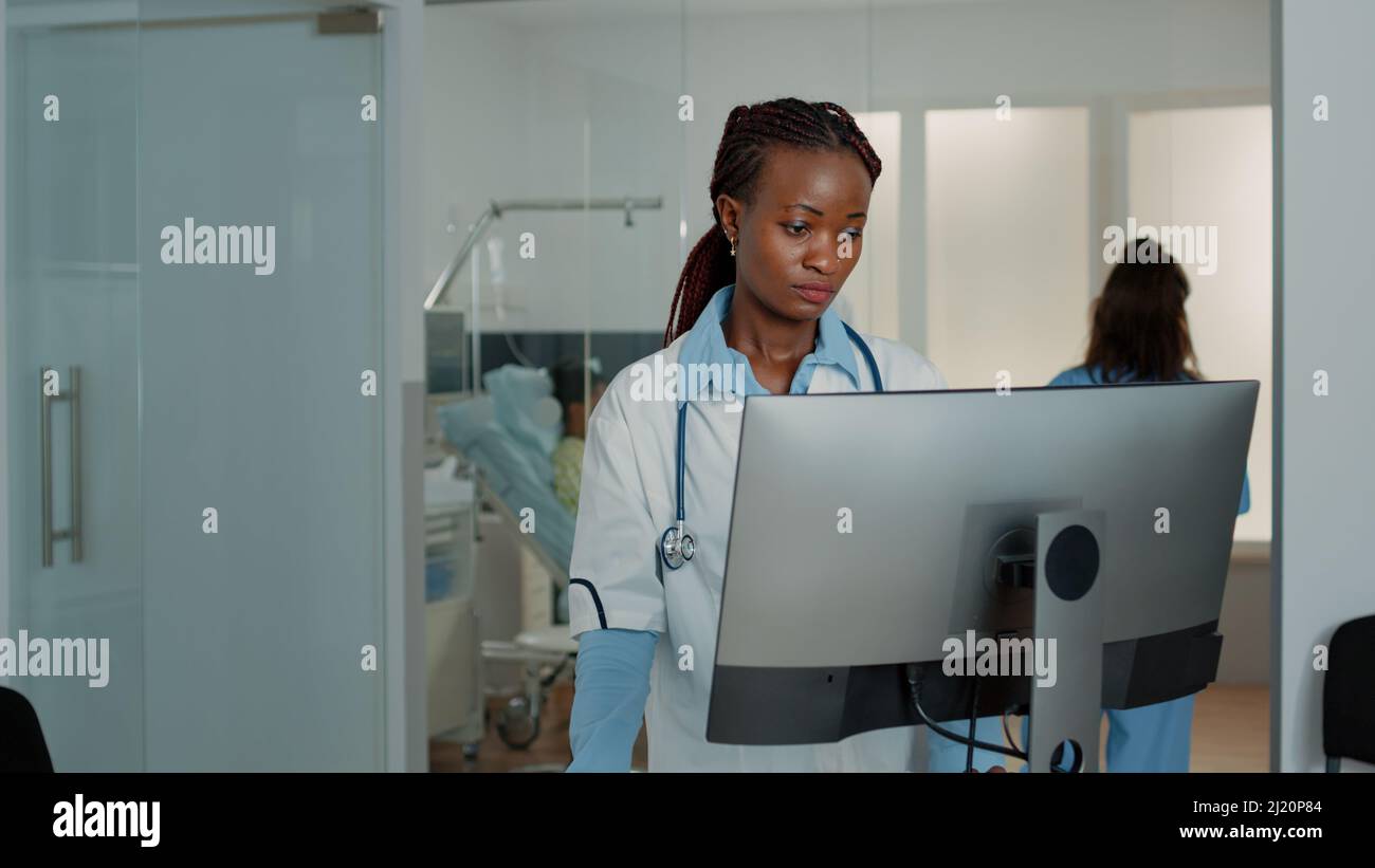 Woman working as doctor with stethoscope using computer to find patient ...