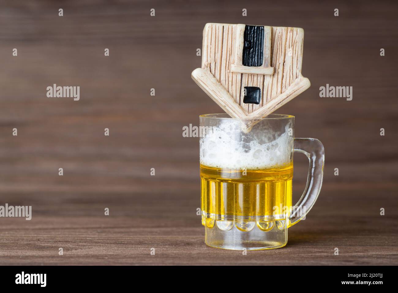 Miniature wooden house flipped upside down on a small beer mug ...