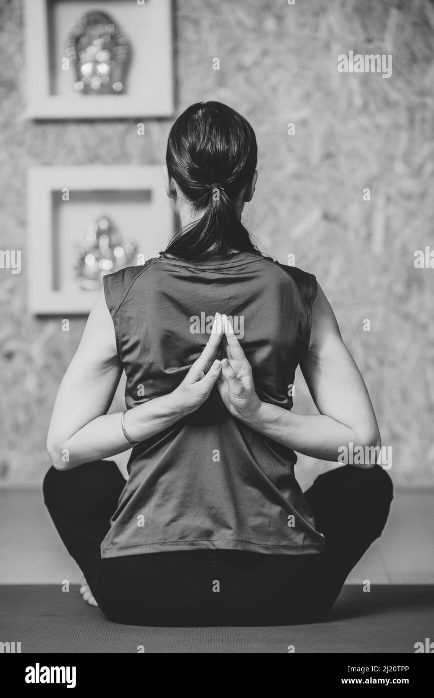 A vertical grayscale shot of a young female practicing yin yoga in a ...