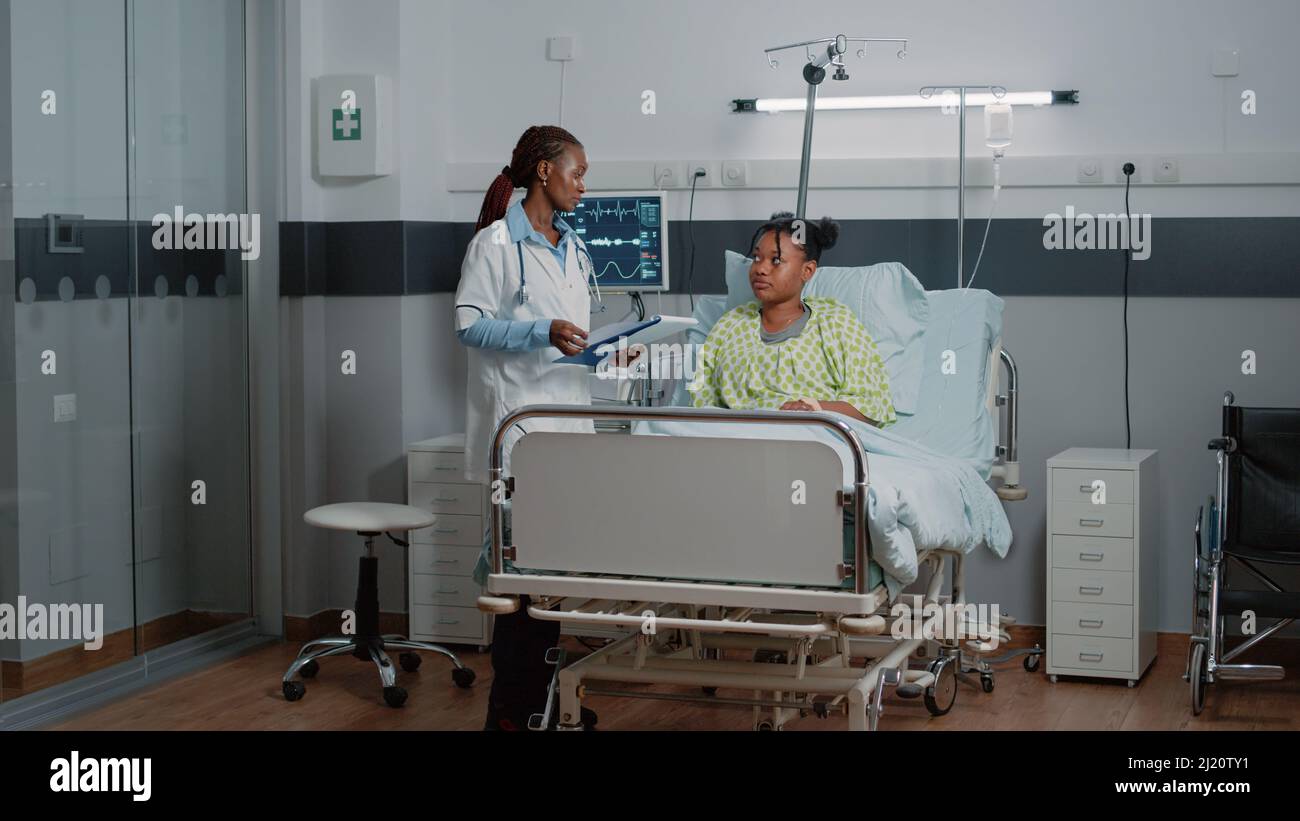 African american doctor doing consultation with patient in bed while ...