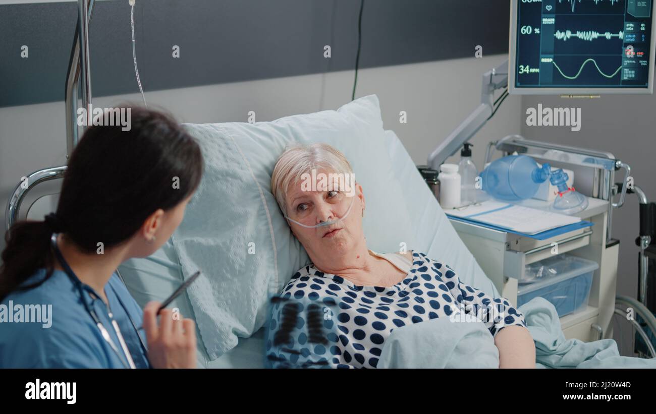 Woman nurse holding x ray scan to old patient for diagnosis and results ...