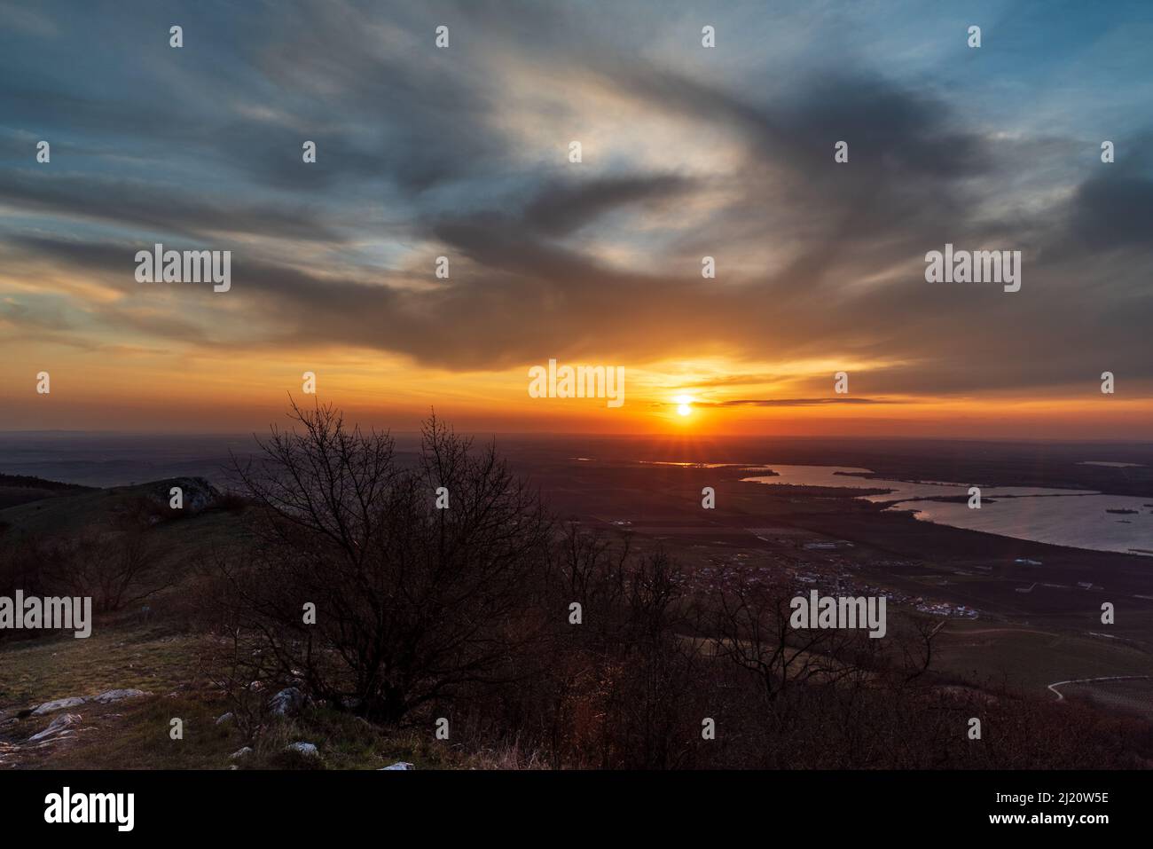 Partly cloudy sunset with orange sky and sun from Devin hill summit in ...