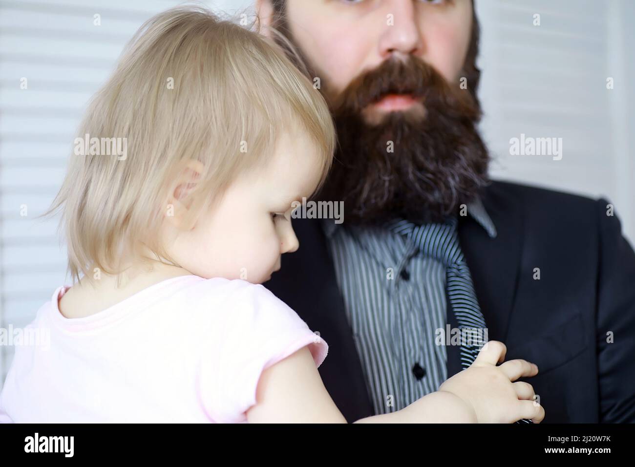 Baby infant hands grab beard of man.Cheerful hipster man curlers in a ...